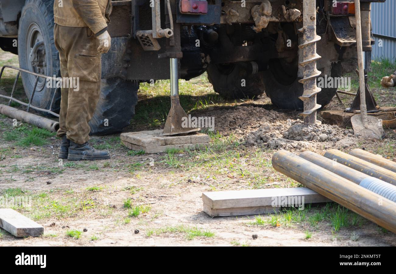 Team of workers with drilling rig on car are drilling artesian well for ...