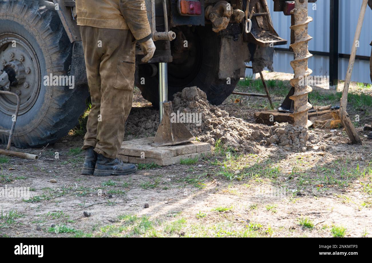 Team of workers with drilling rig on car are drilling artesian well for ...