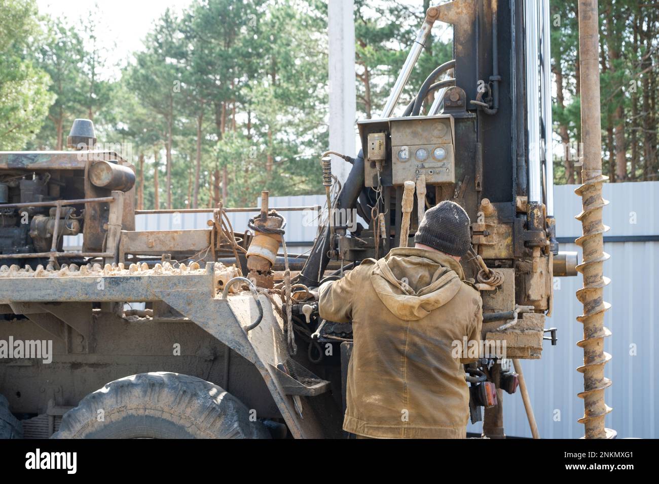 Team of workers with drilling rig on car are drilling artesian well for ...