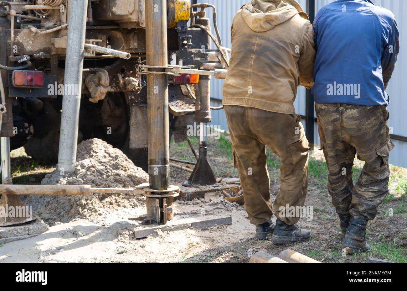 Team of workers with drilling rig on car are drilling artesian well for ...