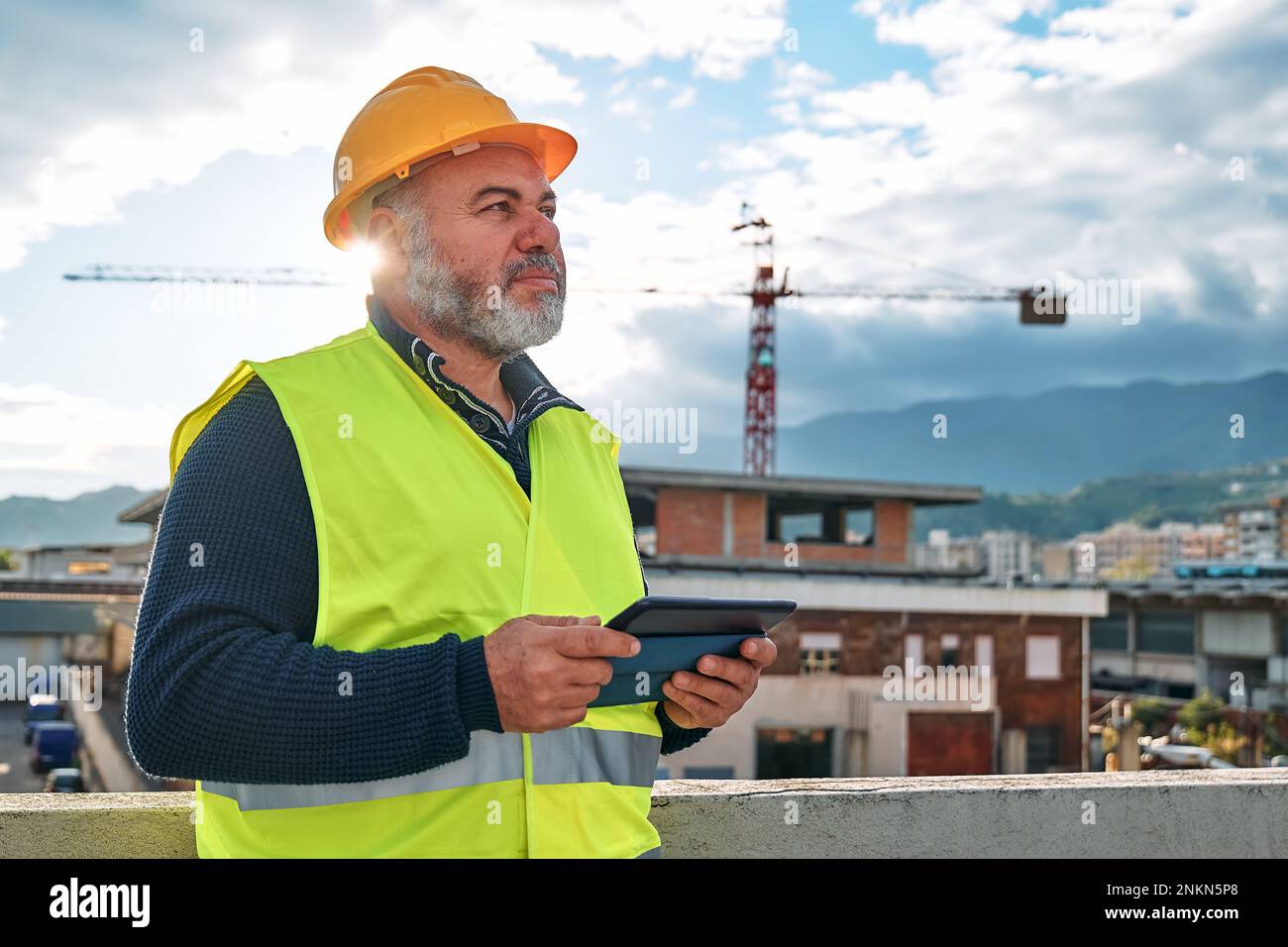 Portrait of middle aged bearded supervisor in hardhat and safety vest ...