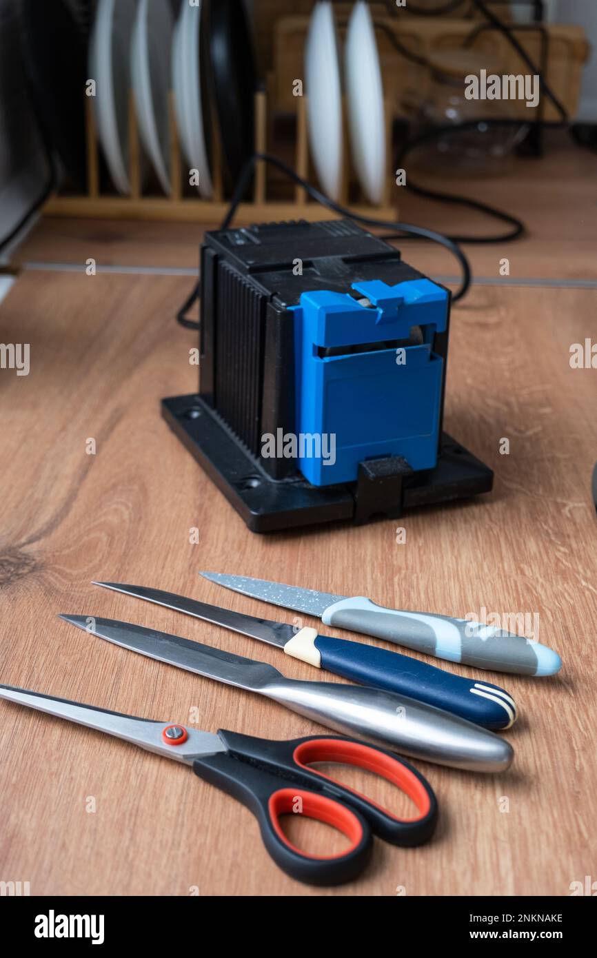Sharpening a knife on an electric sharpener at home. Flatlay knife ...