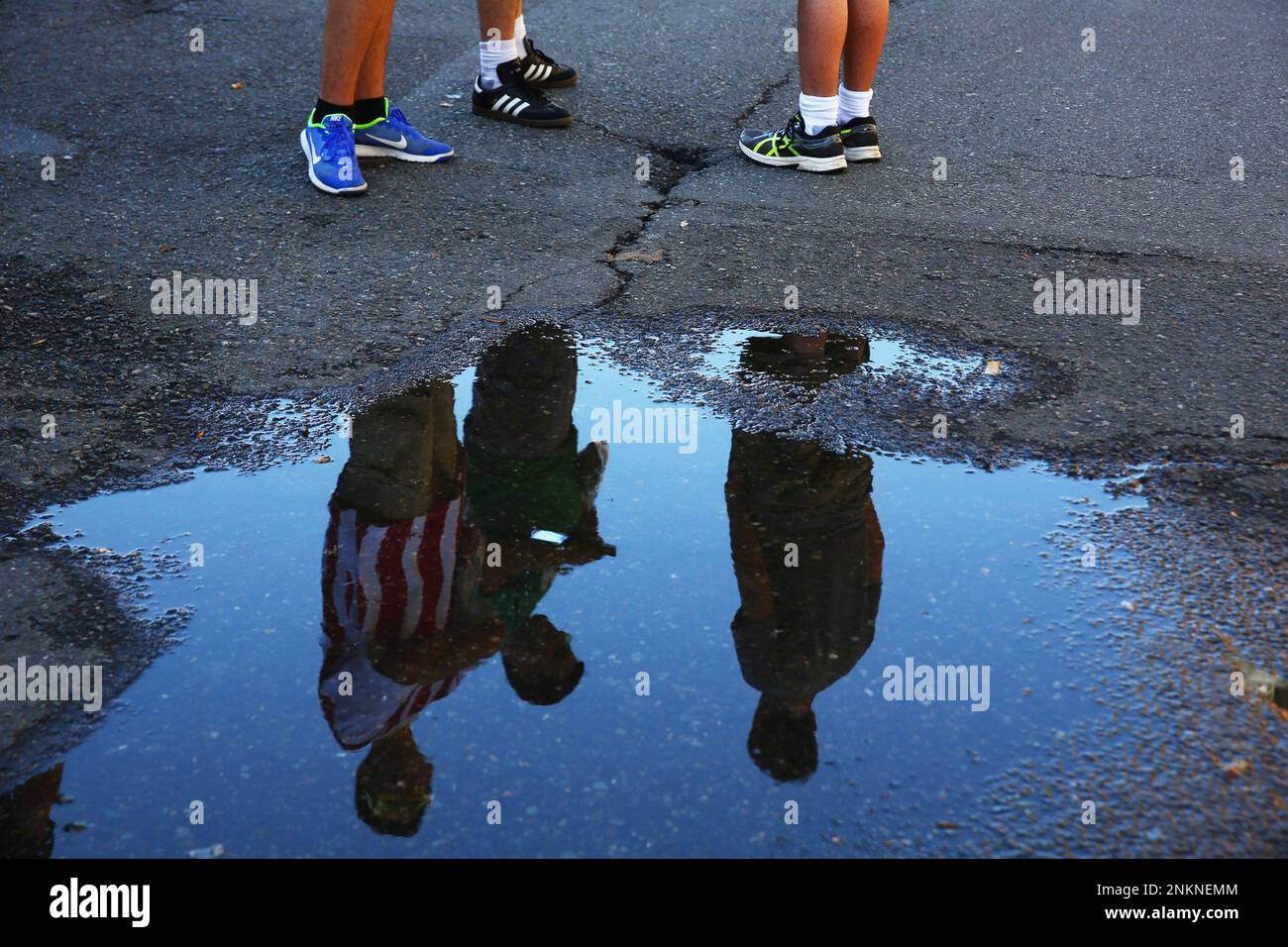 Soccer fans are reflected in a puddle outside of CenturyLink Field ...