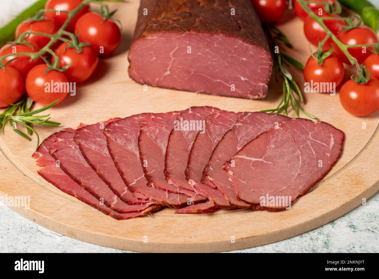 Dry meat. Slices of dried and smoked dry meat on a wooden board. Beef ...