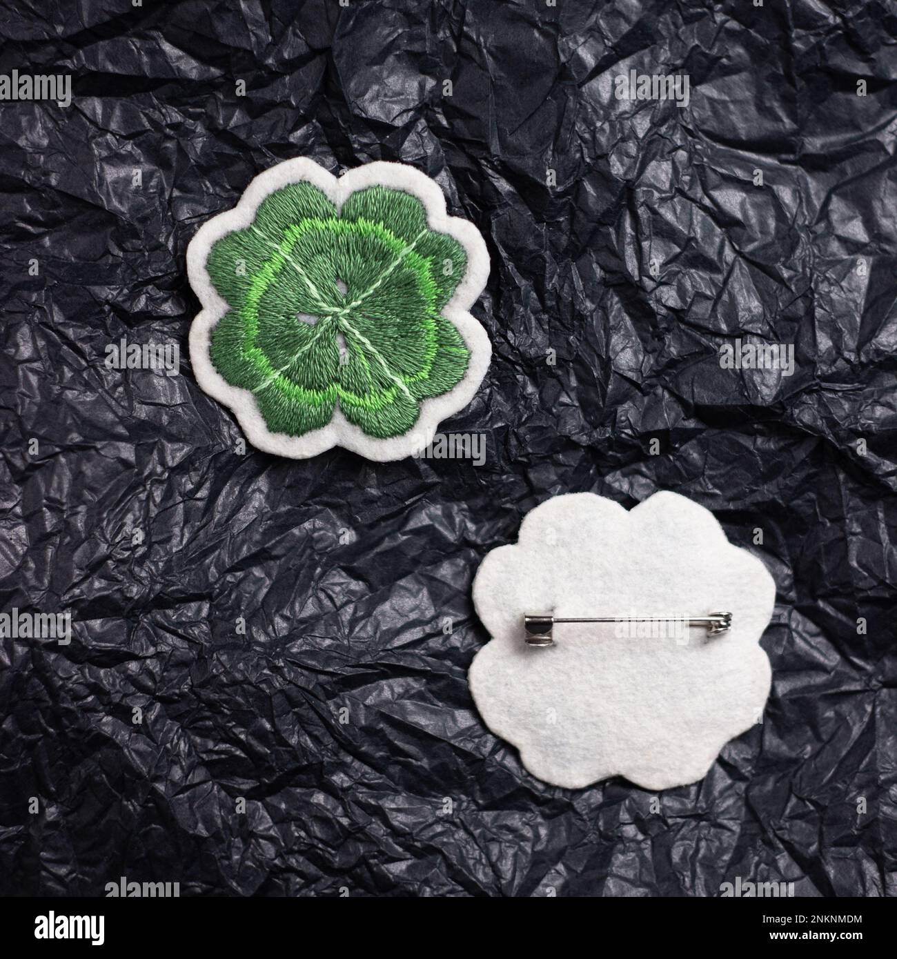 Brooch embroidered with threads on white felt in the form of a clover ...