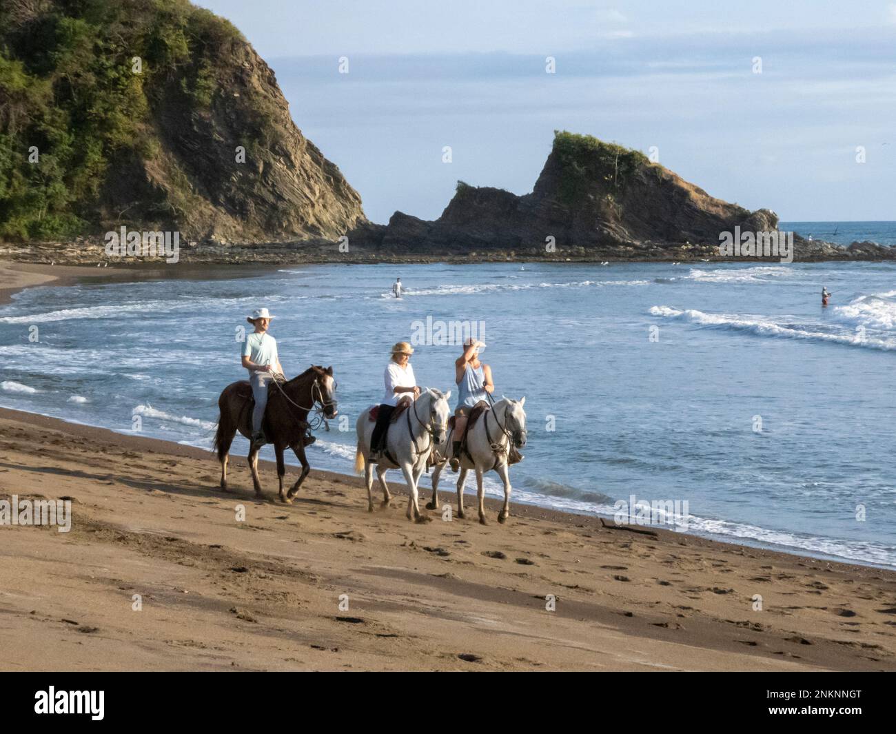 Three people on horseback enjoy a ride along the beach in Samara Costa ...