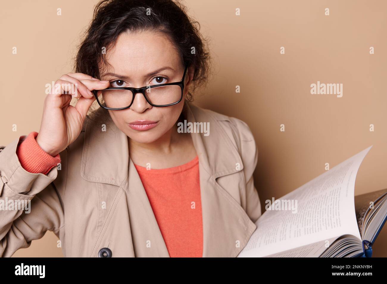 Serious middle-aged female professor or teacher with open book, looking ...