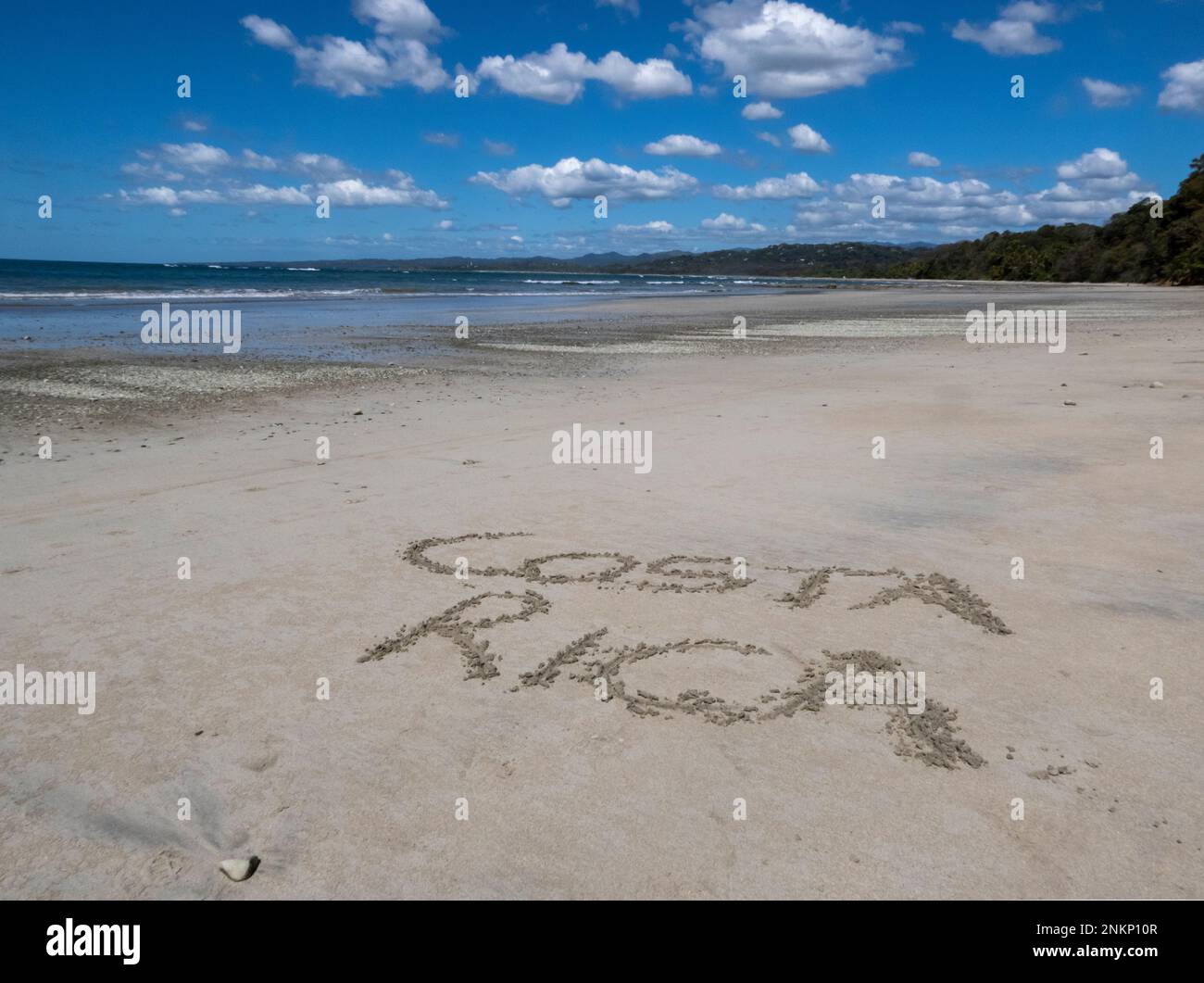 The words Costa Rica is written in the sand on an empty beach on the ...