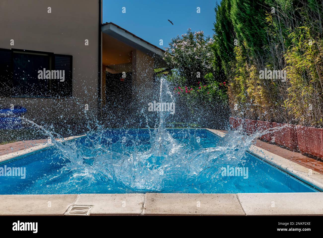 A huge splash of water is created by a cannonball dive into a swimming ...