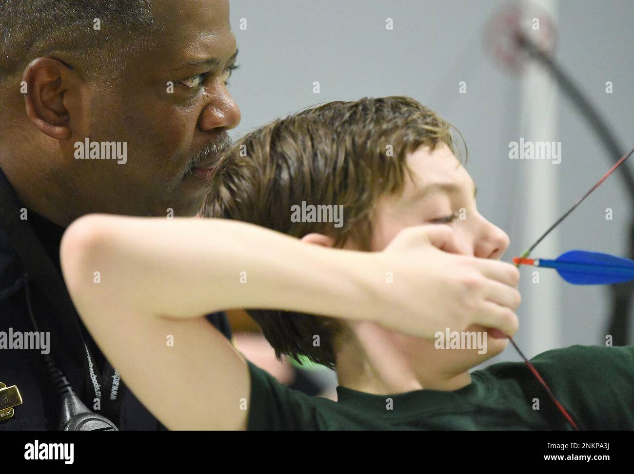 School resource officer Mike Houston watches as Logan Mabry, 11, aims ...