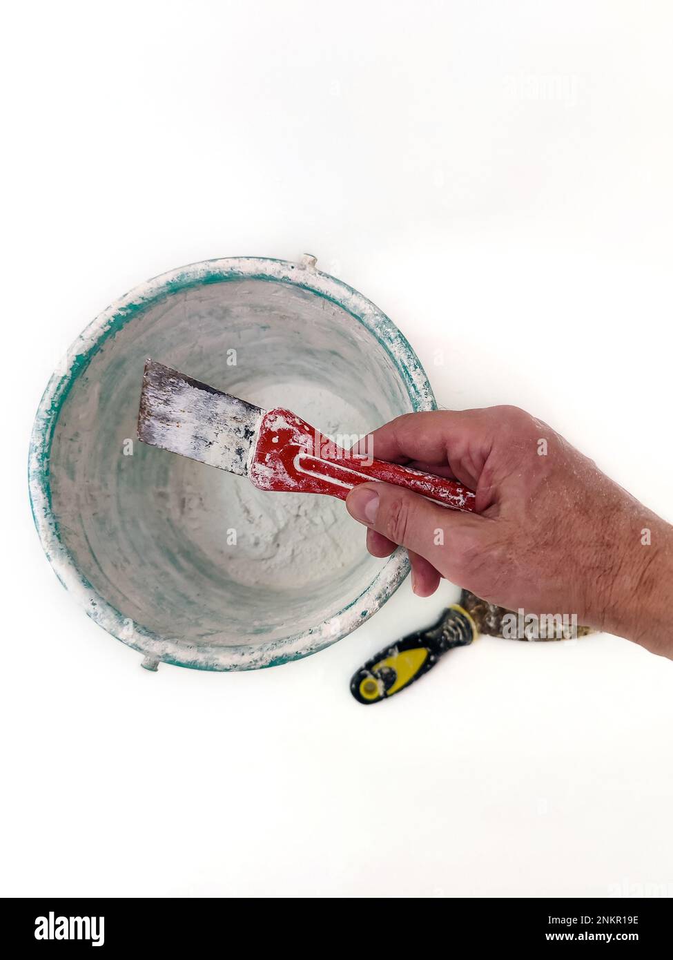Man holds spatula against the background of old plastic bucket. Process ...