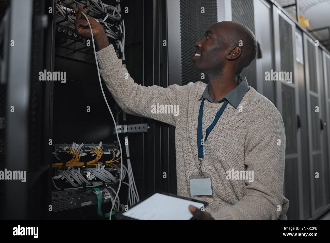 Engineer, server room and black man with cable and tablet for database ...