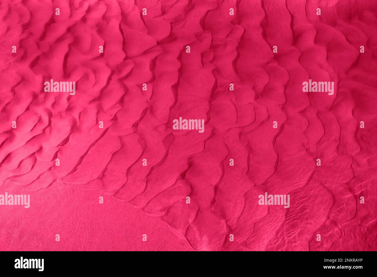 Sand waves in the water with viva magenta color Stock Photo - Alamy