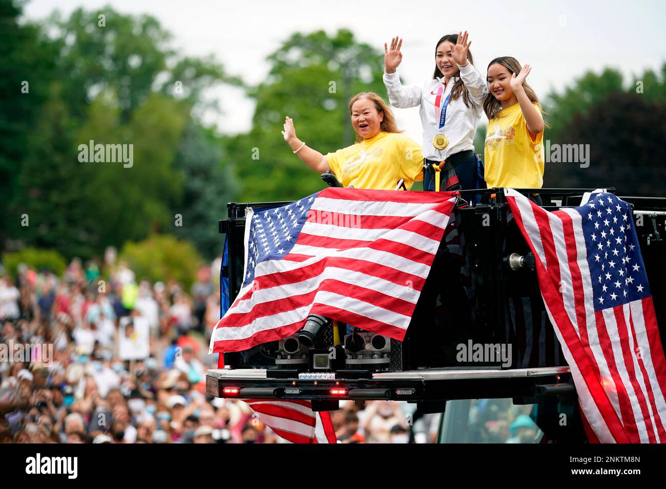 FILE - Olympian Sunisa Lee, center, waves from a St. Paul fire truck with her mom Yeev Thoj ...