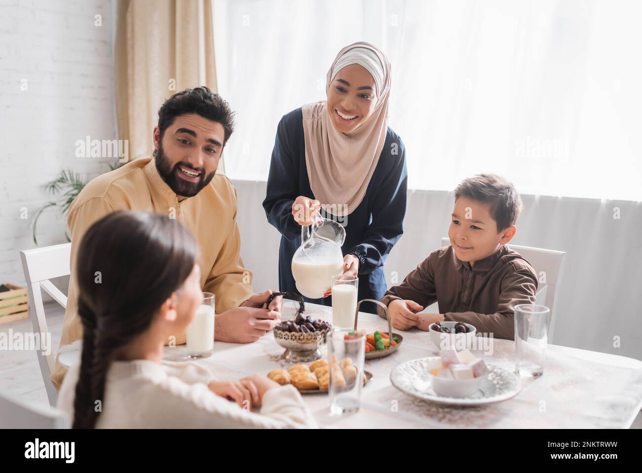 Smiling muslim family looking at daughter during suhur breakfast at ...