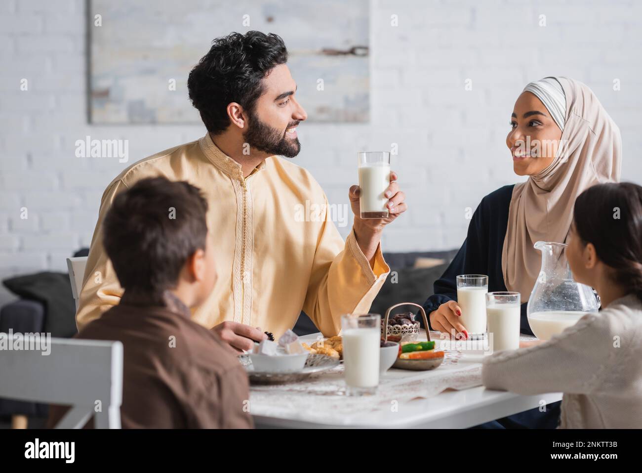 Smiling middle eastern family talking during ramadan breakfast at home ...