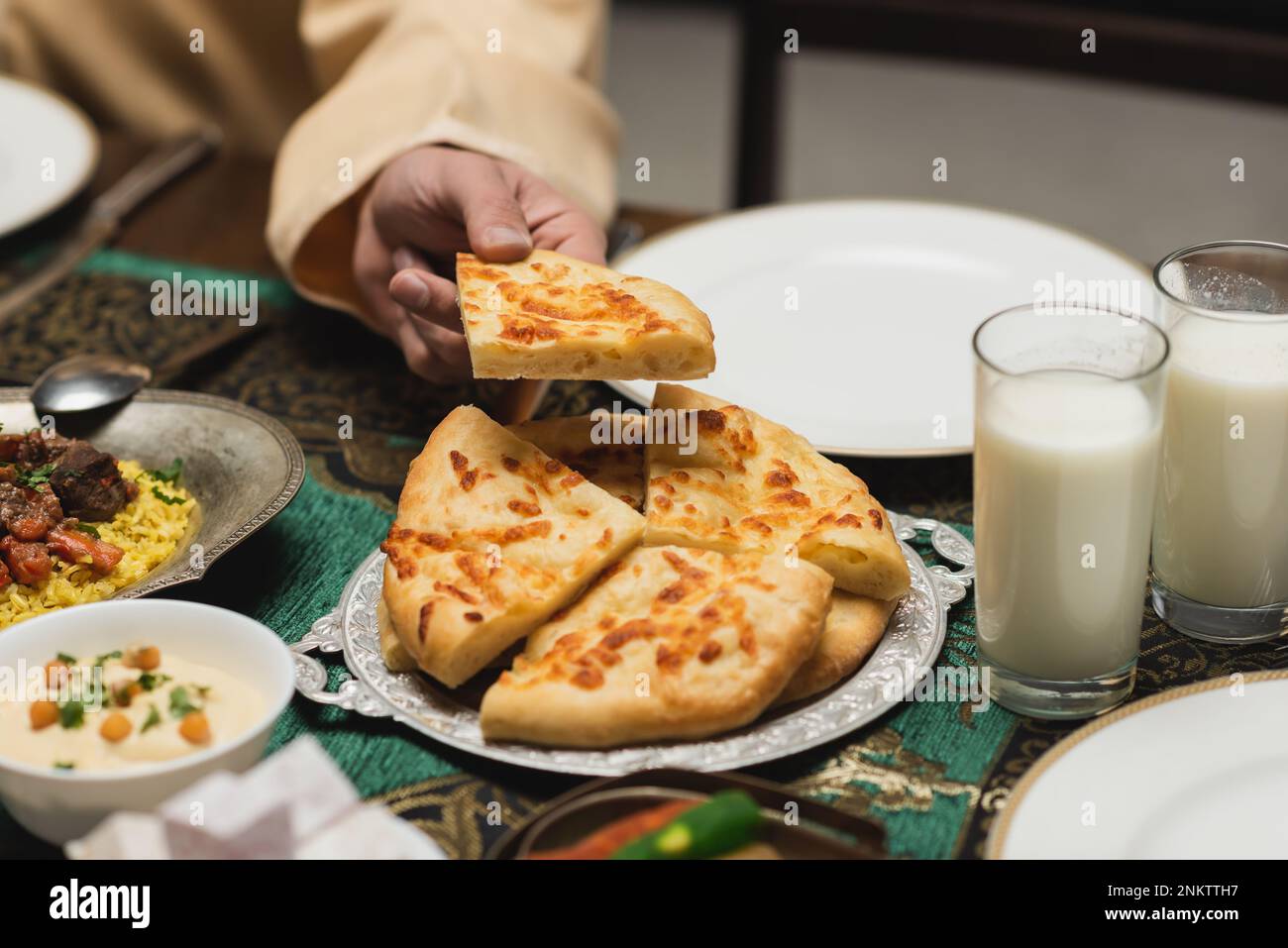 Cropped view of muslim man taking pita bread during ramadan dinner at ...