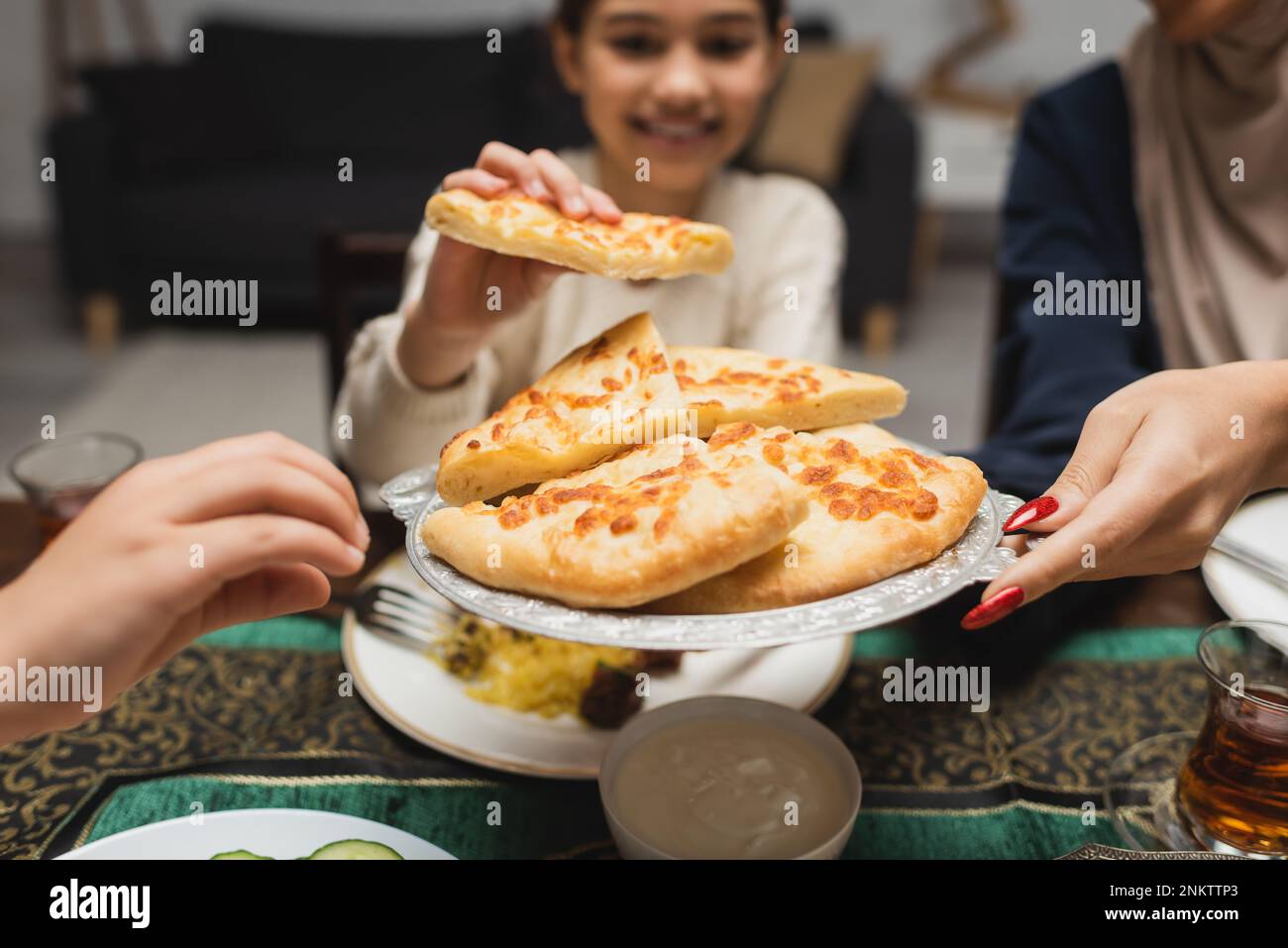 Muslim mother holding pita bread near children during ramadan dinner ...