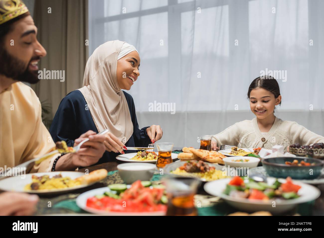 Smiling middle eastern family talking during ramadan dinner at home ...