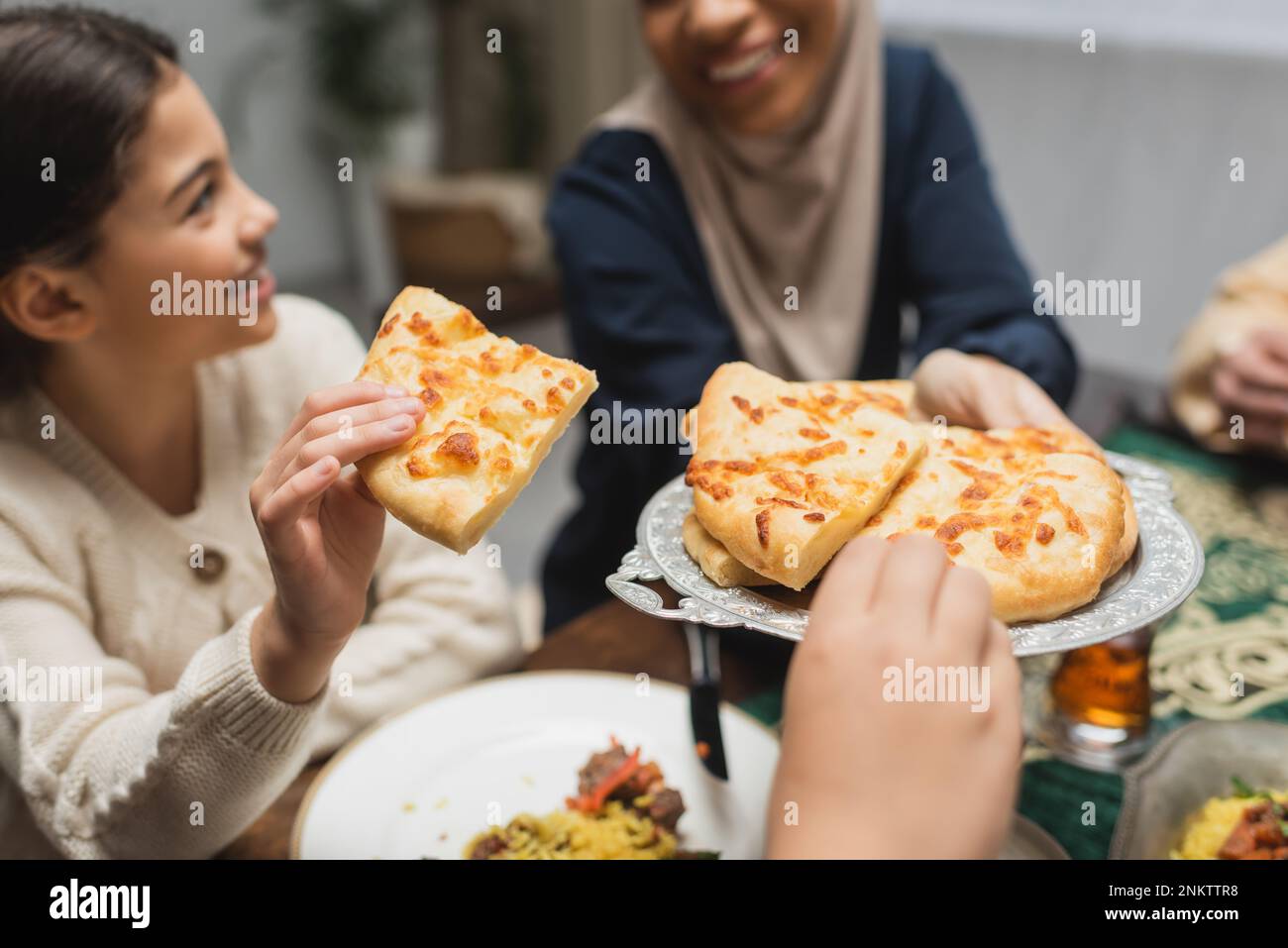 Muslim mother holding pita bread near children and ramadan dinner,stock ...