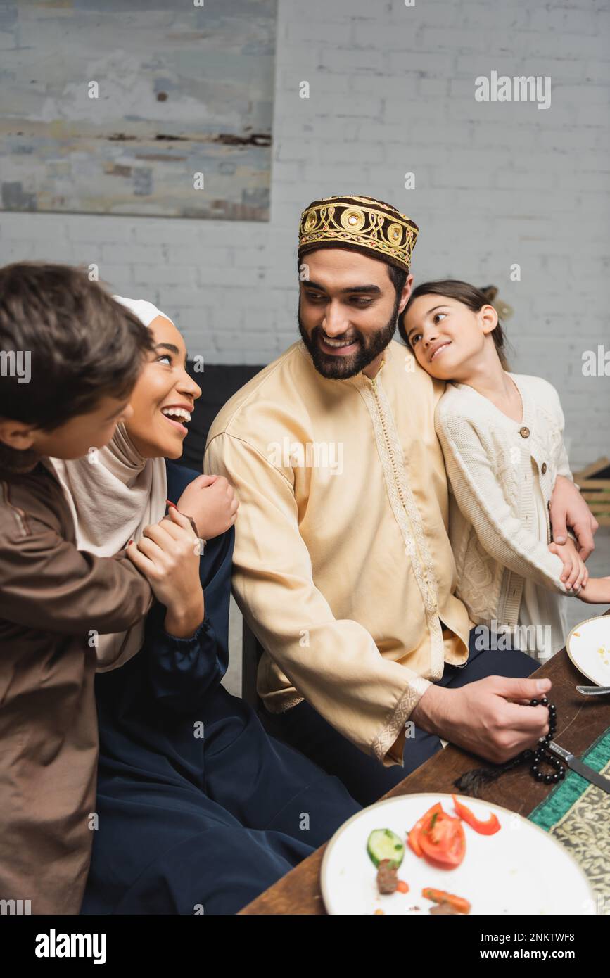 Smiling arabian man hugging daughter and looking at family during ...