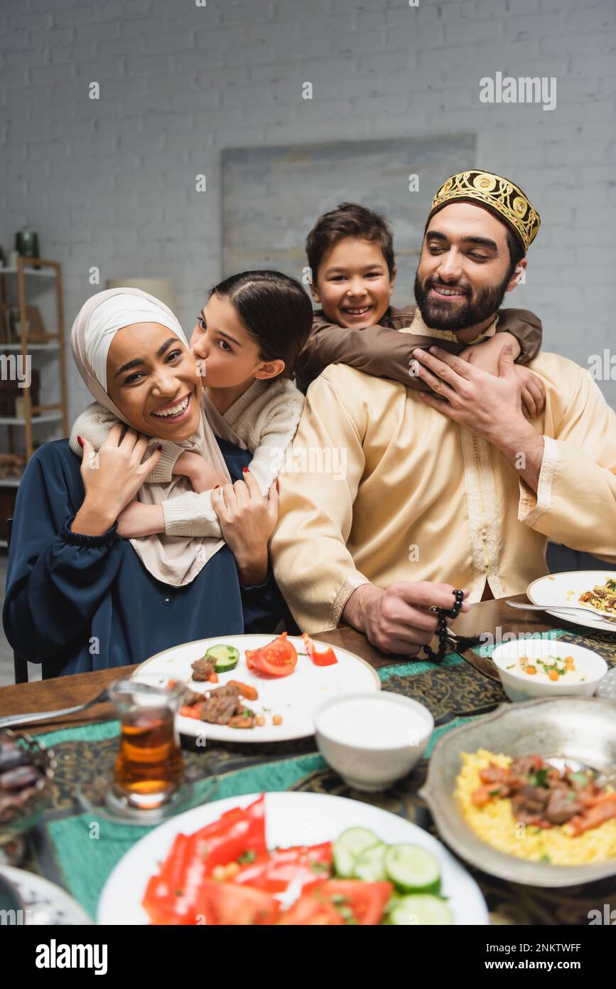Cheerful middle eastern family hugging near food during ramadan at home ...