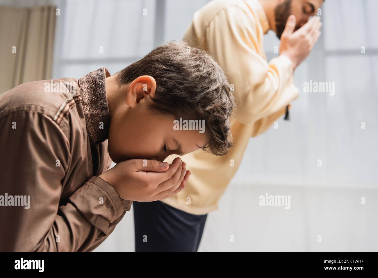 Side view of muslim kid praying near blurred father during salah,stock ...