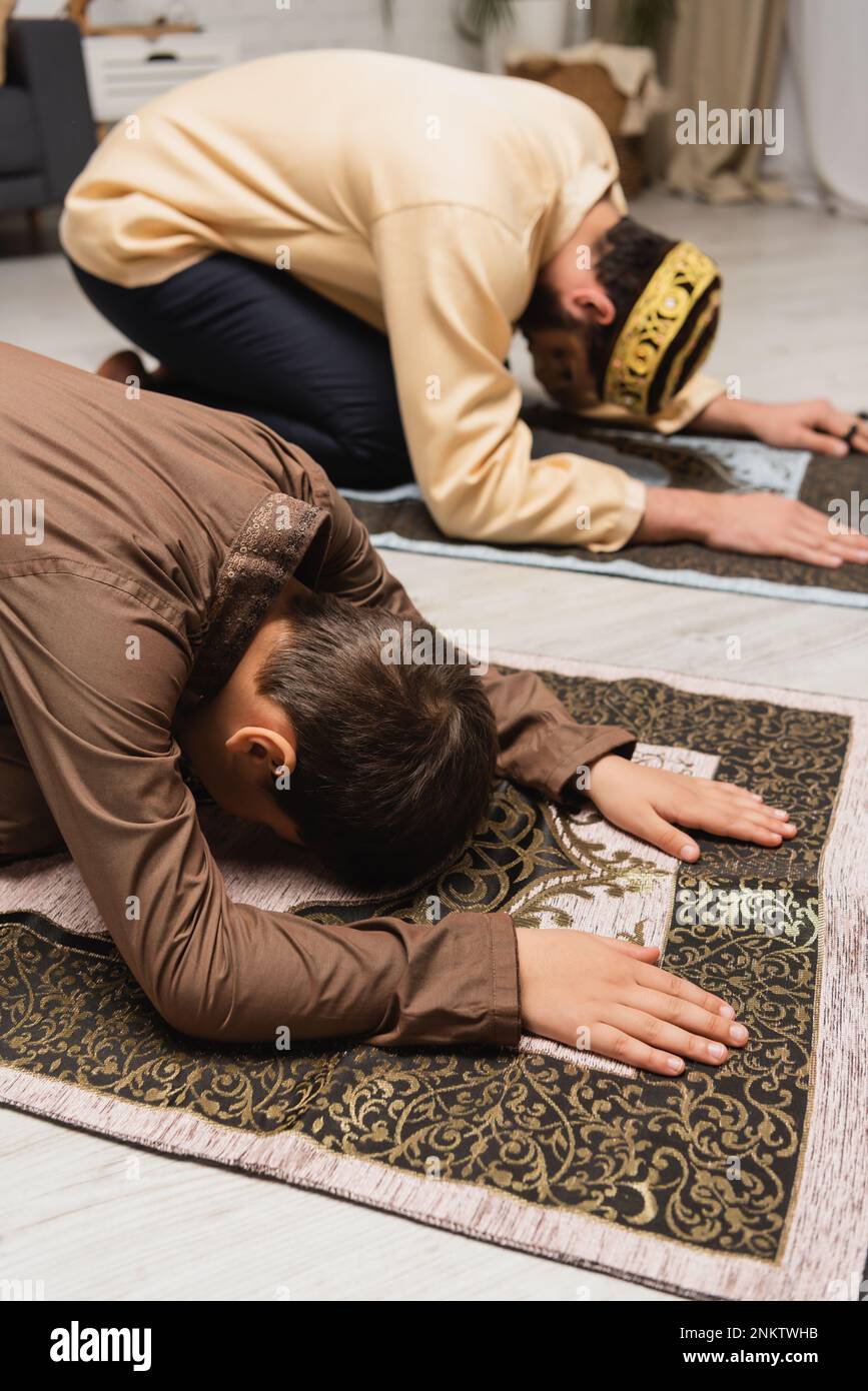 Muslim boy praying on rug near blurred father during ramadan,stock ...