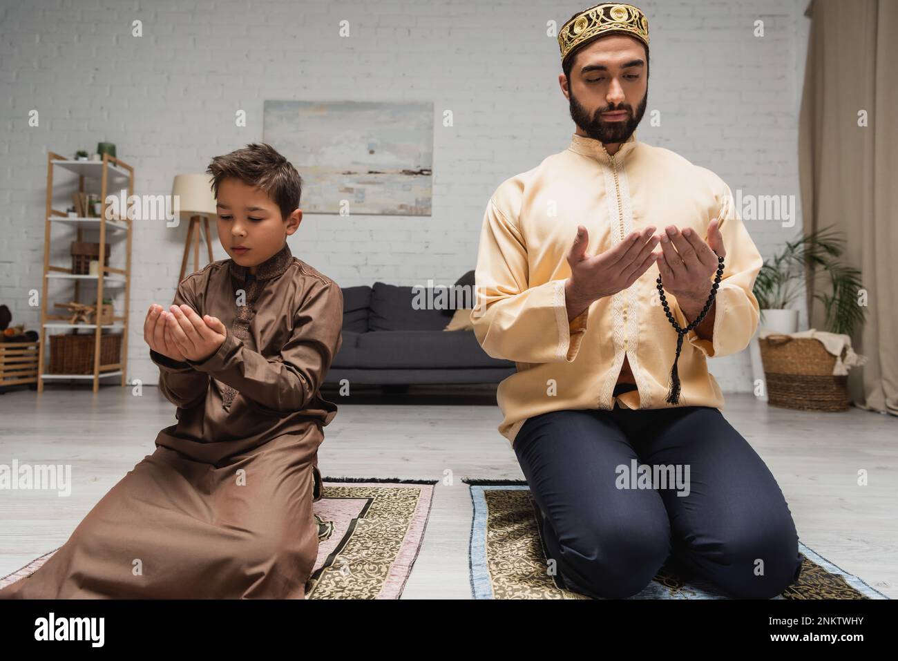 Muslim man and son praying on rugs during ramadan at home,stock image ...