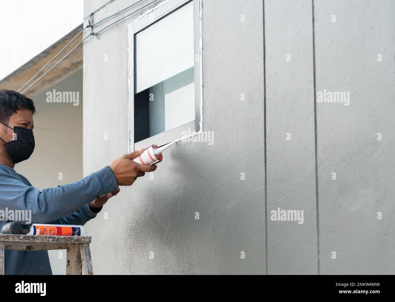 Worker applying silicone sealant window frame rim in building site Stock Photo - Alamy