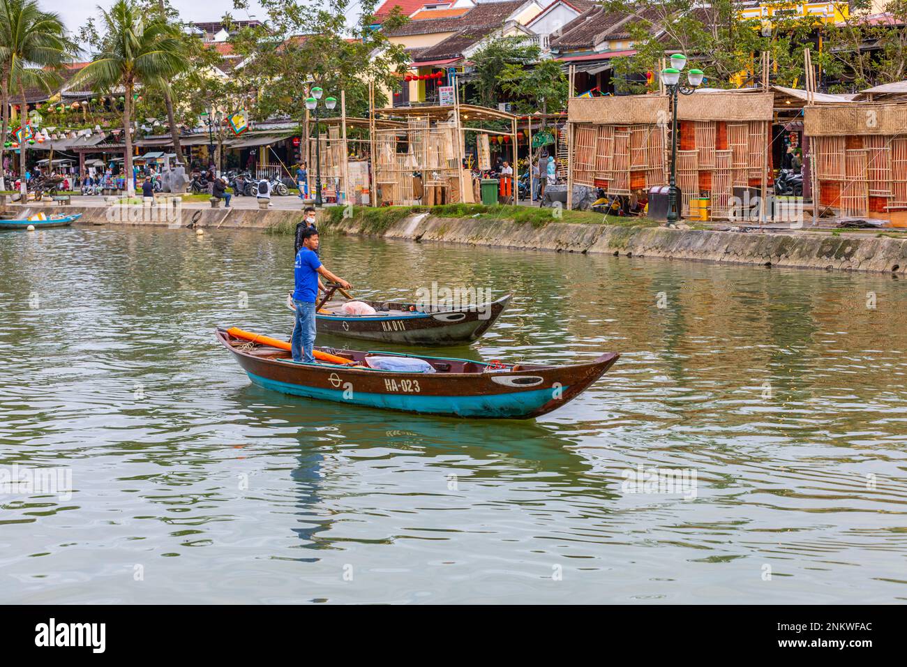 Two young men paddling small boats down Thu Bon River in Hoi An ...