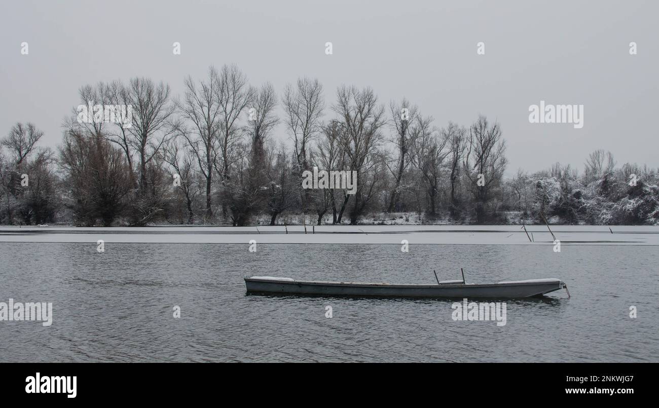 A boat sailing down a river, surrounded by a snow-covered landscape ...