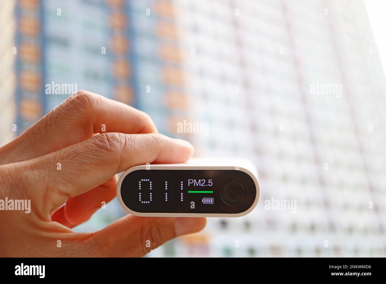 Closeup of a person holding an air pollution sensor against high ...