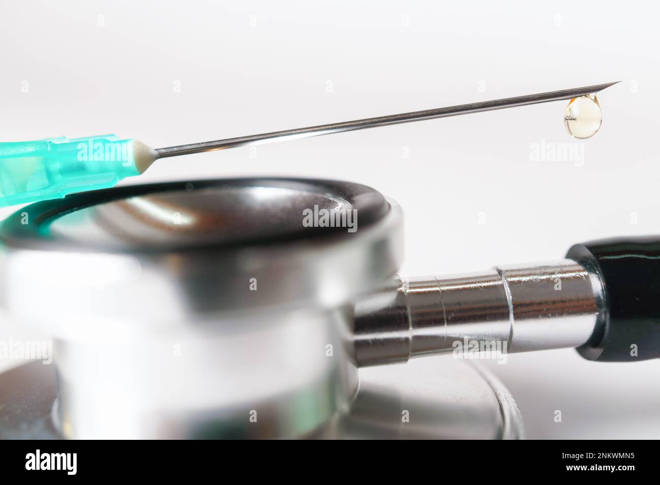 close-up of a syringe needle with a droplet falling on a white ...