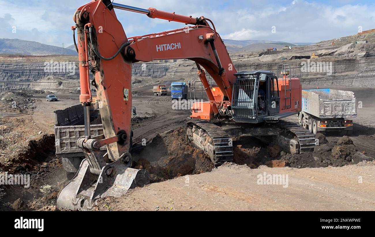 Excavator is loading continuously the trucks, working at a huge mining ...