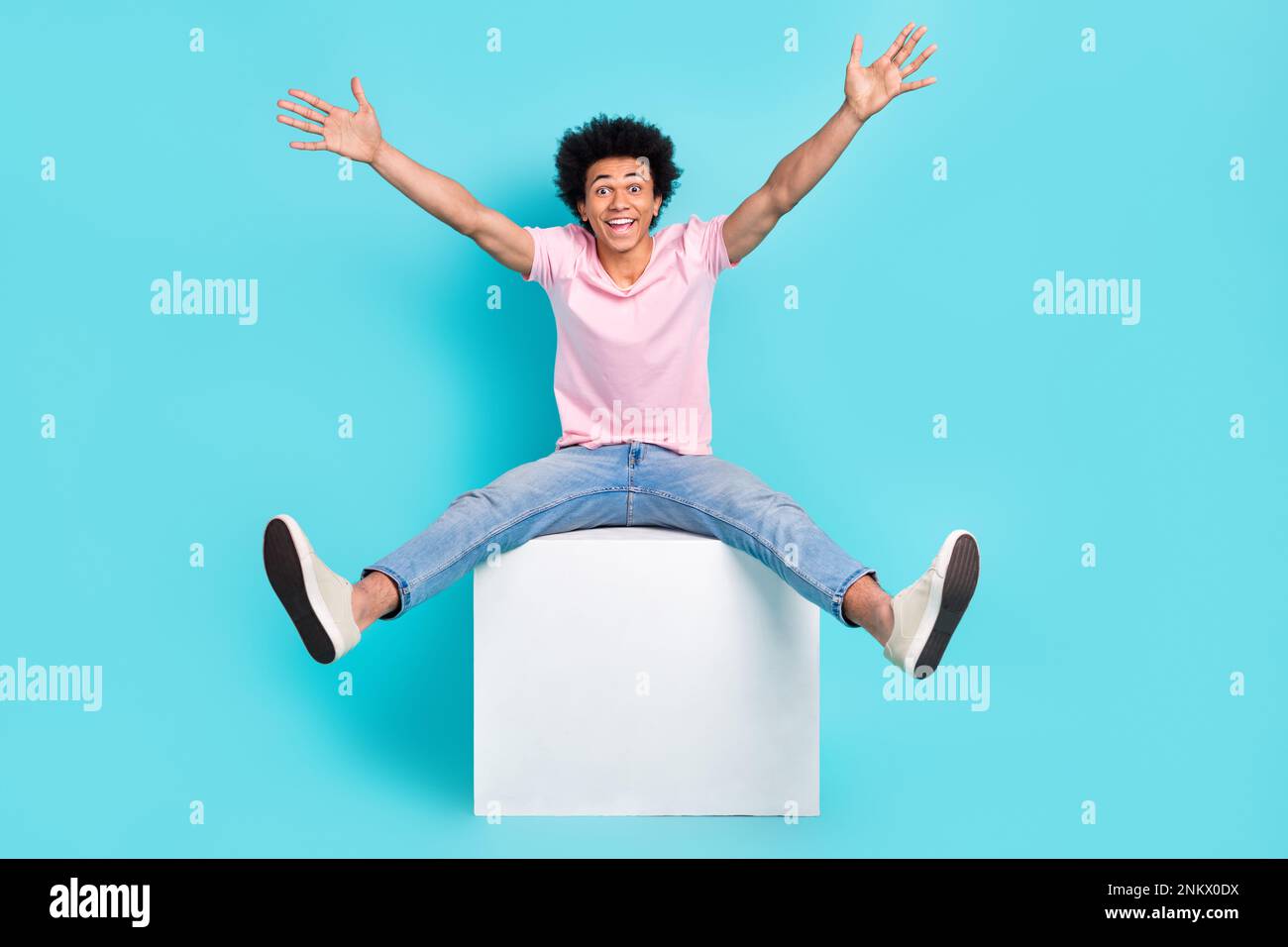 Full length photo cadre of overjoyed guy sit white box raise hands up ...