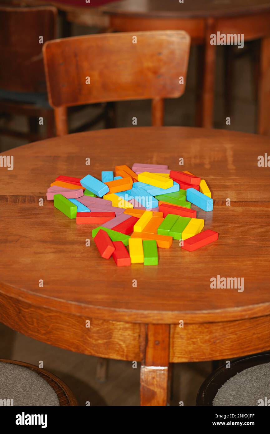 The ruined tower of Jenga game. Colored blocks scattered on table ...