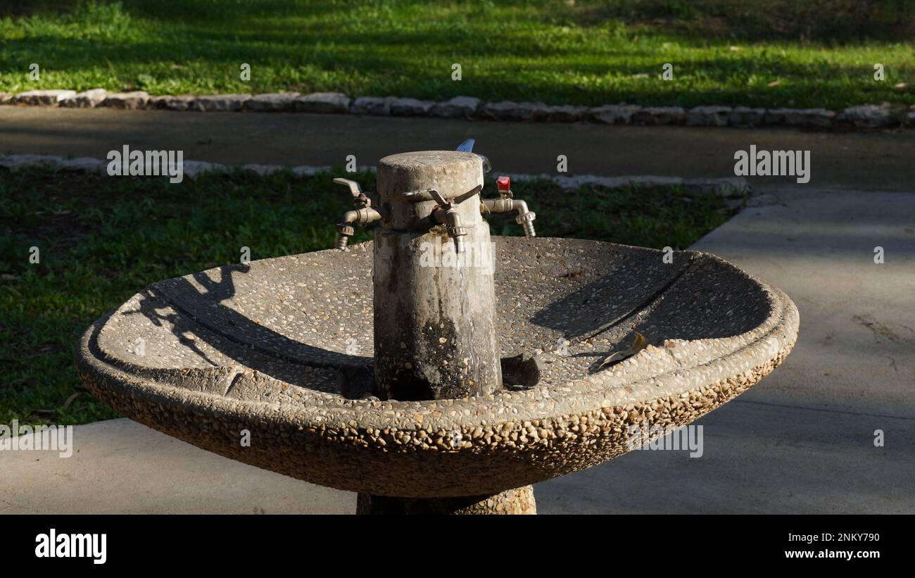 Water faucets in a public park. The round stone fountain serves as a ...