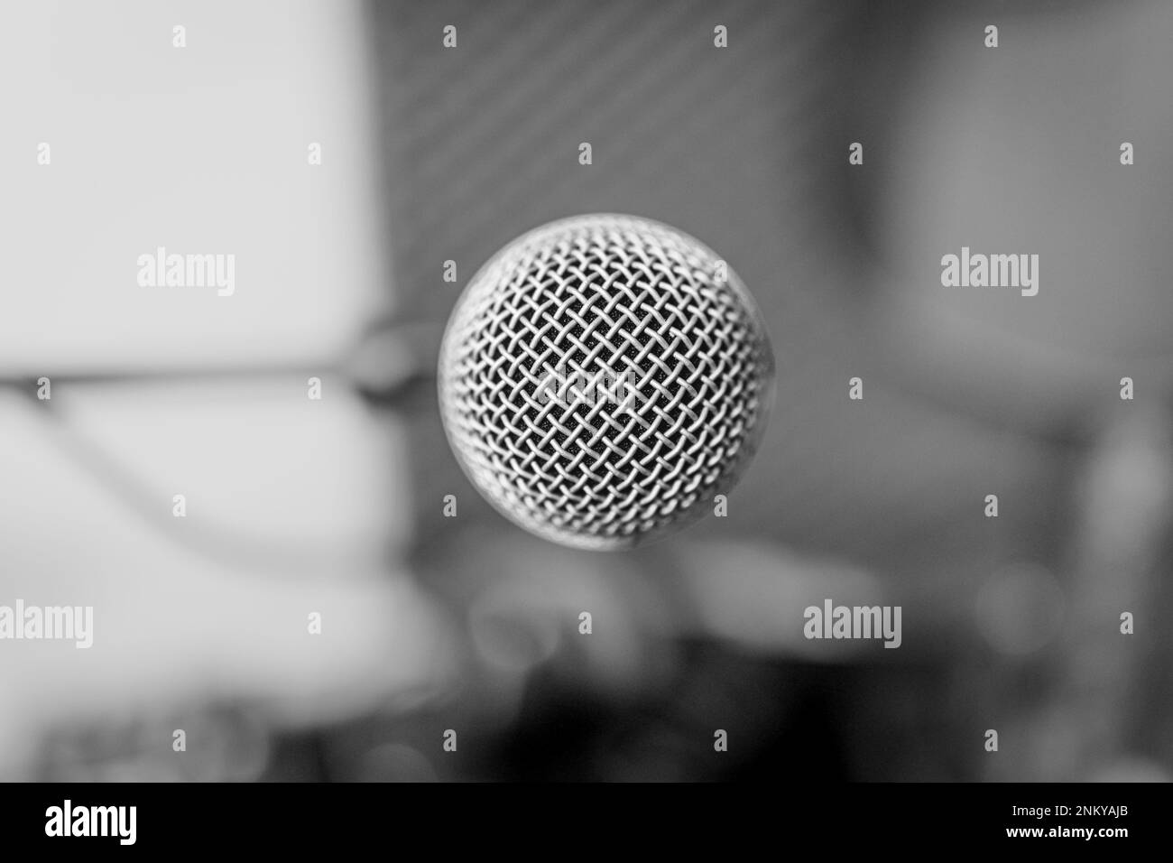 A closeup of a microphone positioned in front of a sound mixing board ...