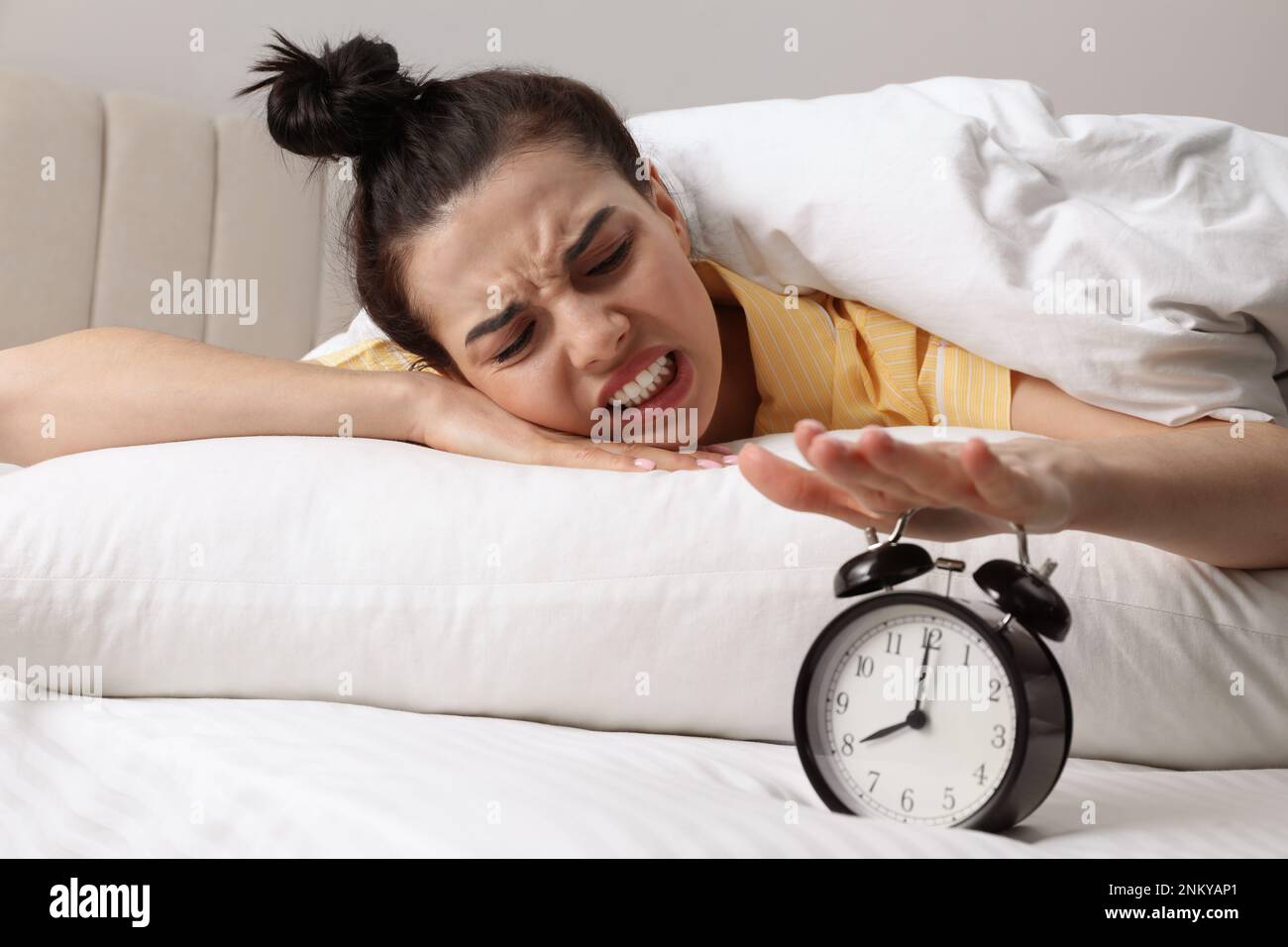 Emotional overslept woman with alarm clock in bed. Being late concept ...