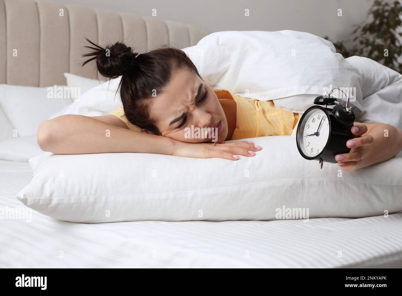 Emotional overslept woman with alarm clock in bed. Being late concept ...