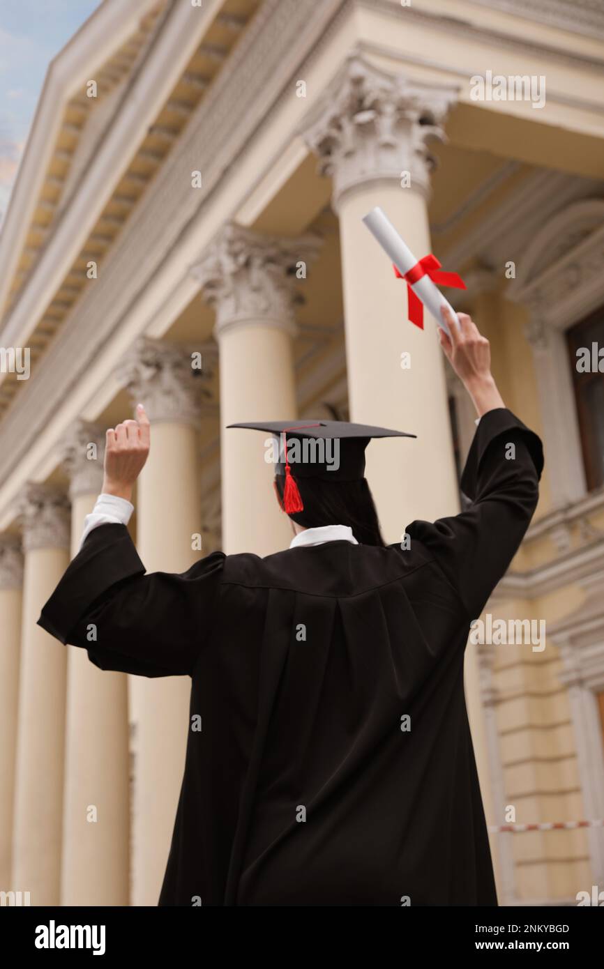 Student with diploma after graduation ceremony outdoors, back view ...