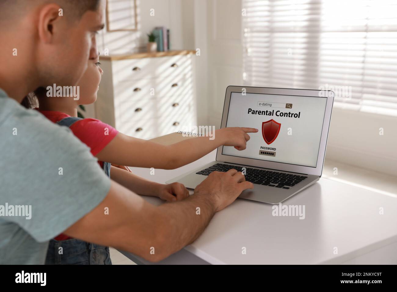 Father installing parental control app on laptop to ensure his child's ...