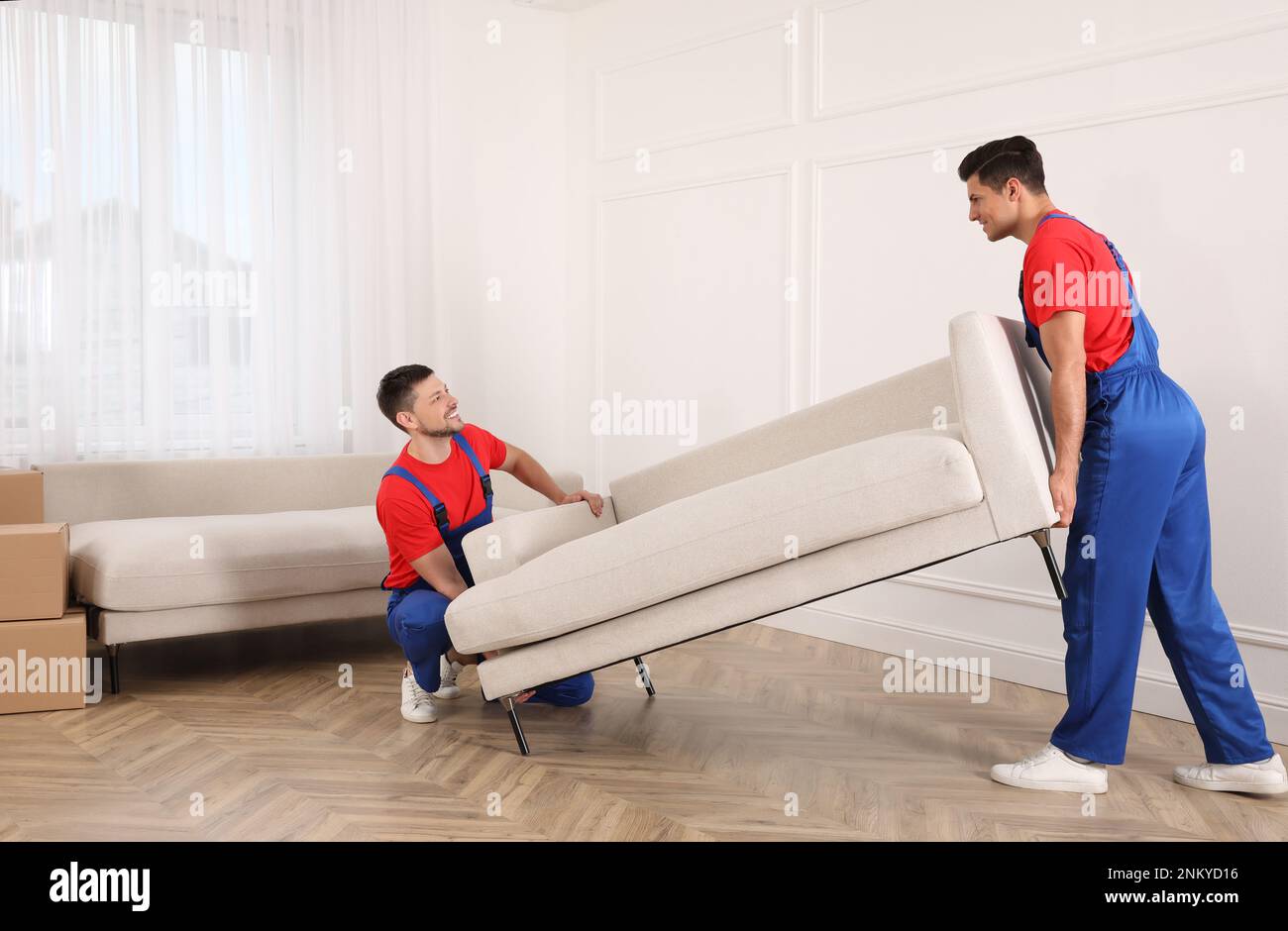 Professional movers carrying sofa in new house Stock Photo - Alamy
