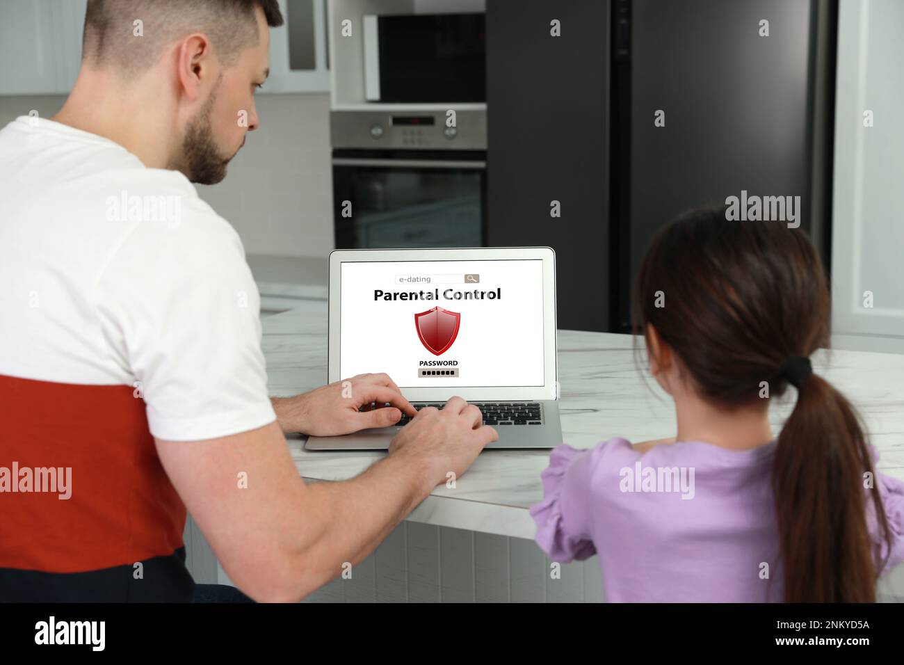 Dad installing parental control on laptop at table in kitchen, back ...