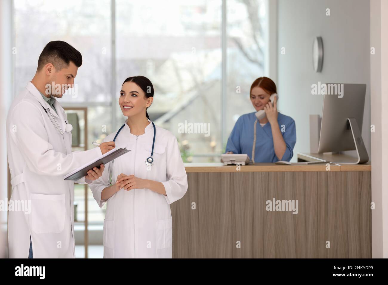 Doctors working near receptionist while she talking on phone in ...