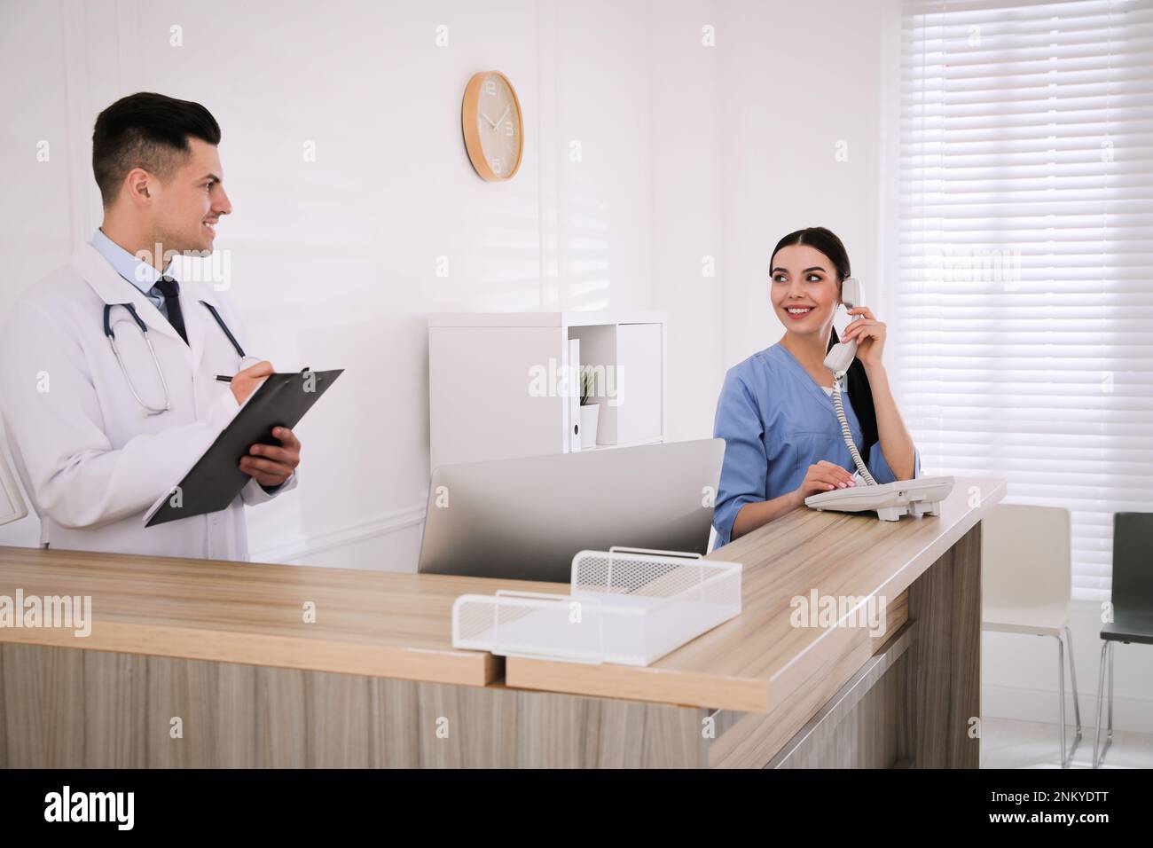 Receptionist and doctor working at countertop in hospital Stock Photo ...
