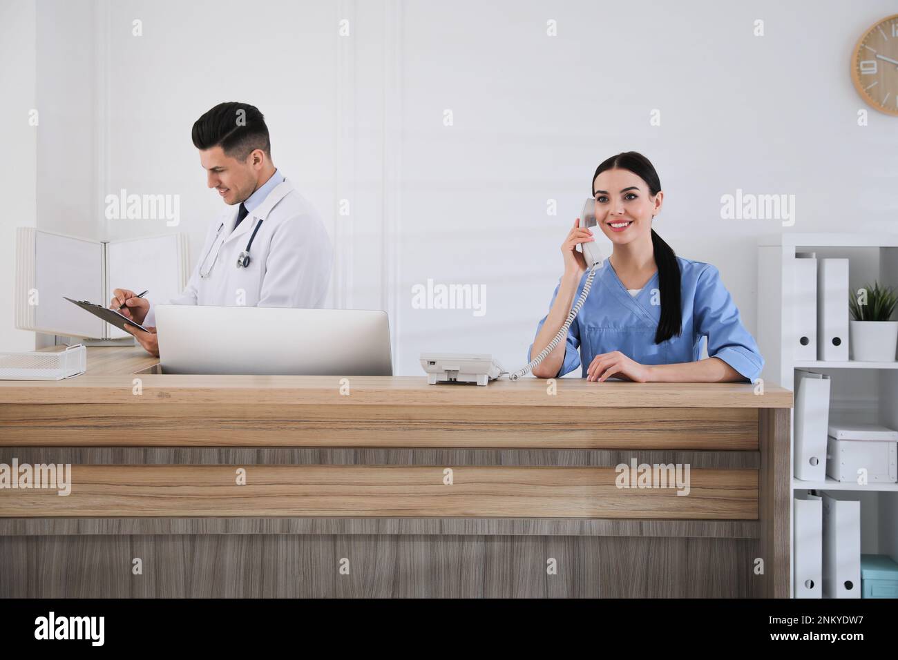 Receptionist and doctor working at countertop in hospital Stock Photo ...
