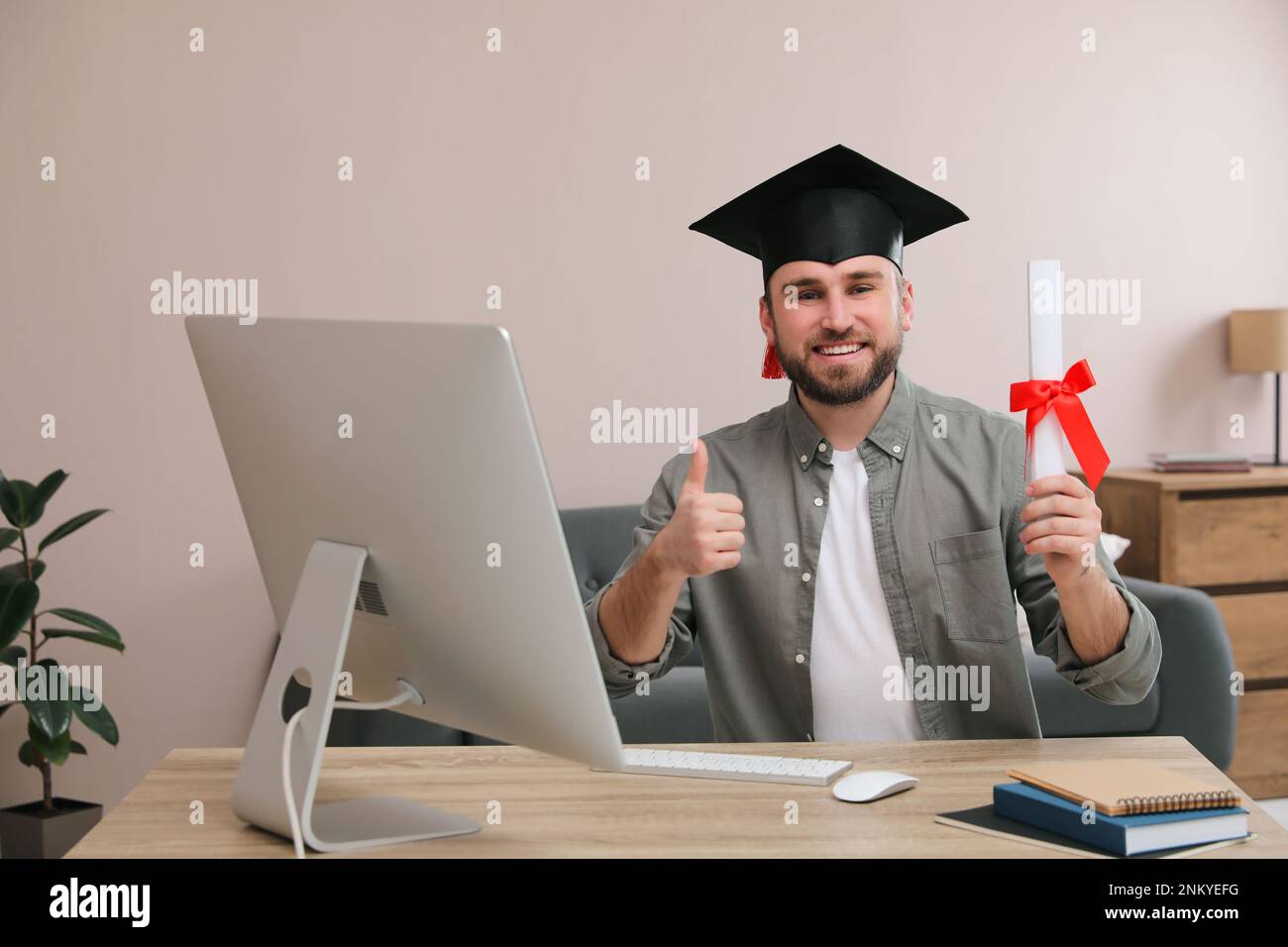 Happy student with graduation hat and diploma at workplace in office ...