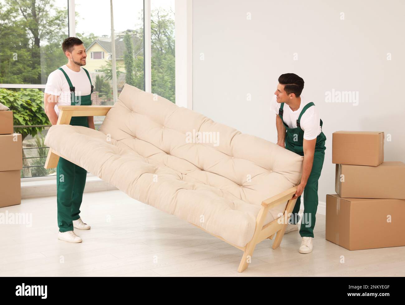 Professional movers carrying sofa in new house Stock Photo - Alamy